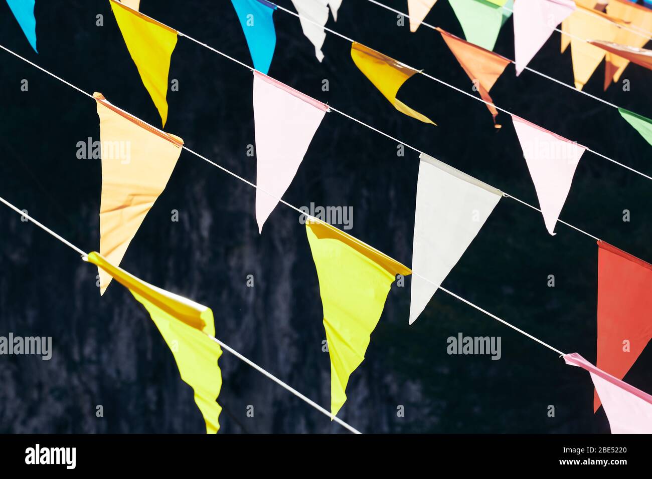 Multi colored triangular flags hanging on the ropes on a dark ...