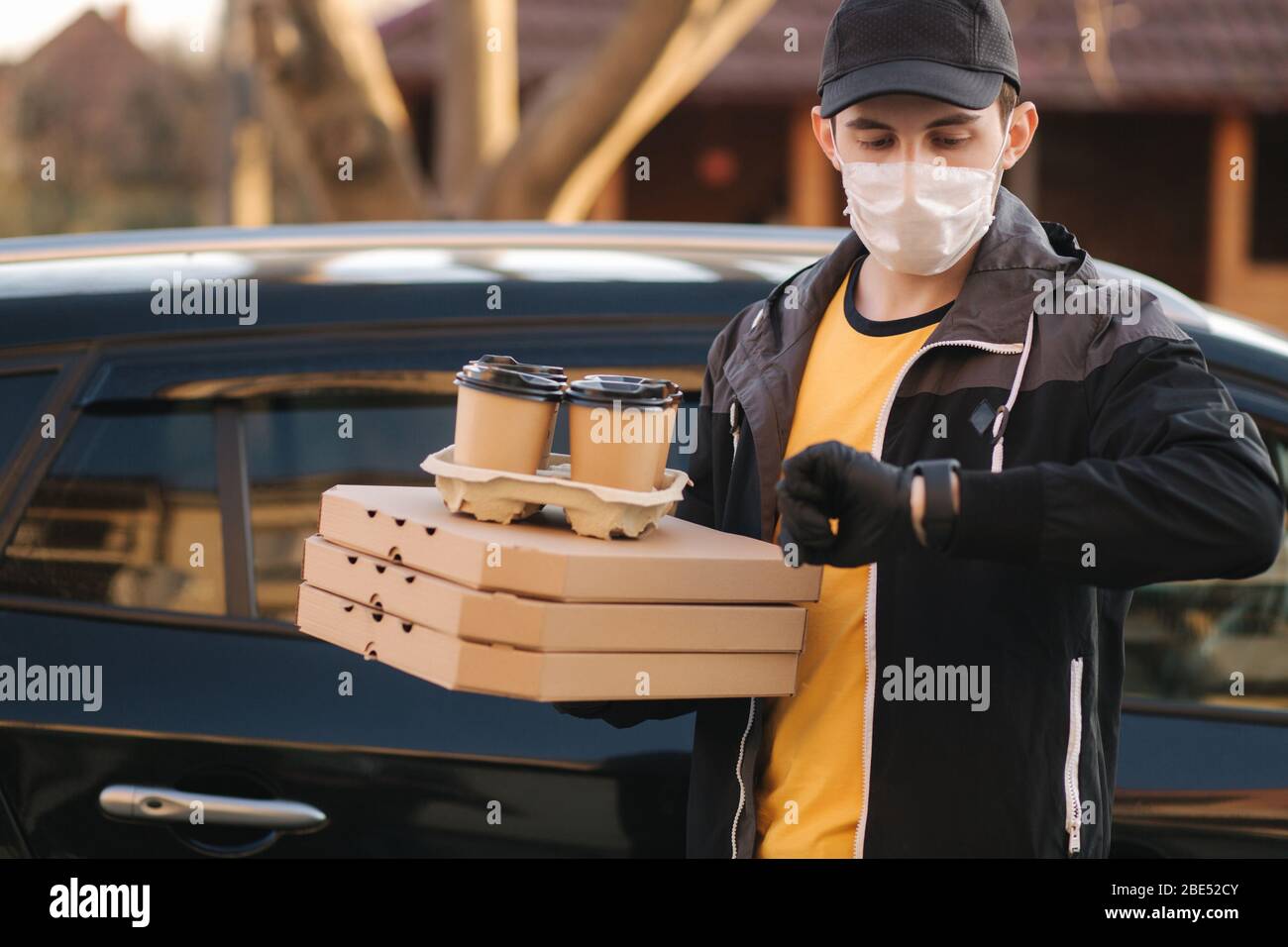 Courier in protective mask and medical gloves wait for customer ...