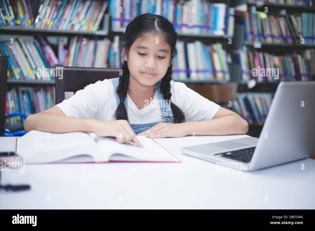 Asian girl students reading books and using notebook in the library ...