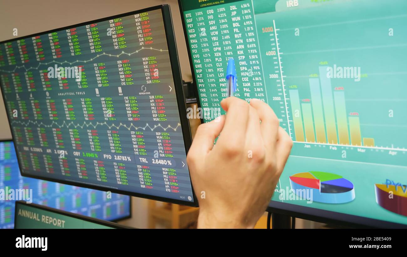 Close up of stock market trader hand on monitors with financial graphs ...
