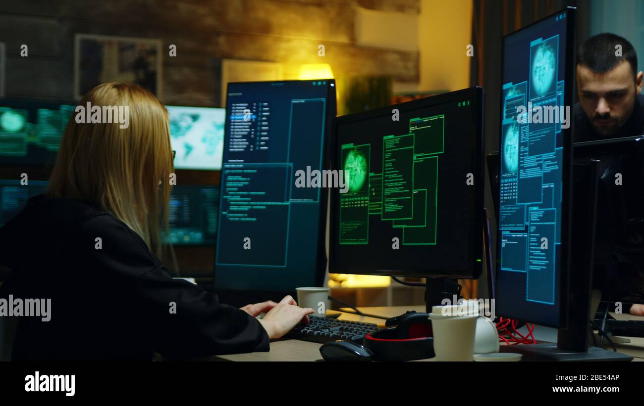 Beautiful hacker girl working with another dangerous cyber criminals ...