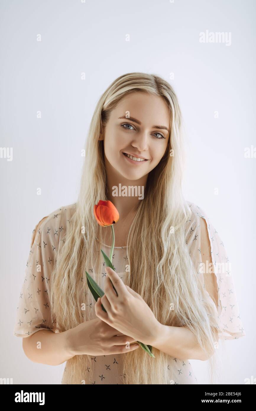 Happy woman holding one red tulip indoors. Portrait on tender girl in ...
