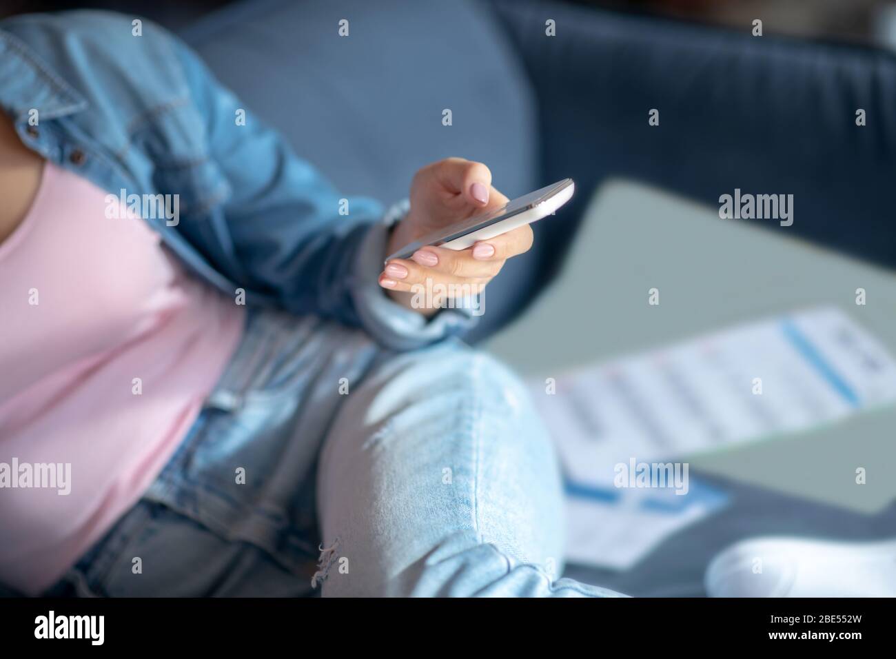 Woman sitting on sofa, holding remote control Stock Photo - Alamy