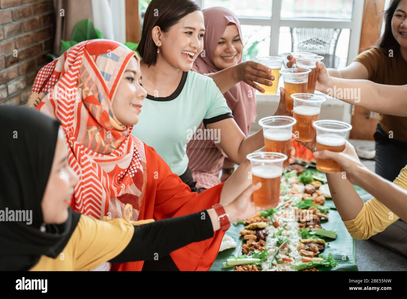 woman social gathering cheering their glass together while lunch with ...