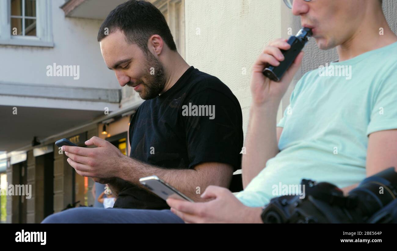 Man smoking electronic sigarette outdoor near another guy Stock Photo ...