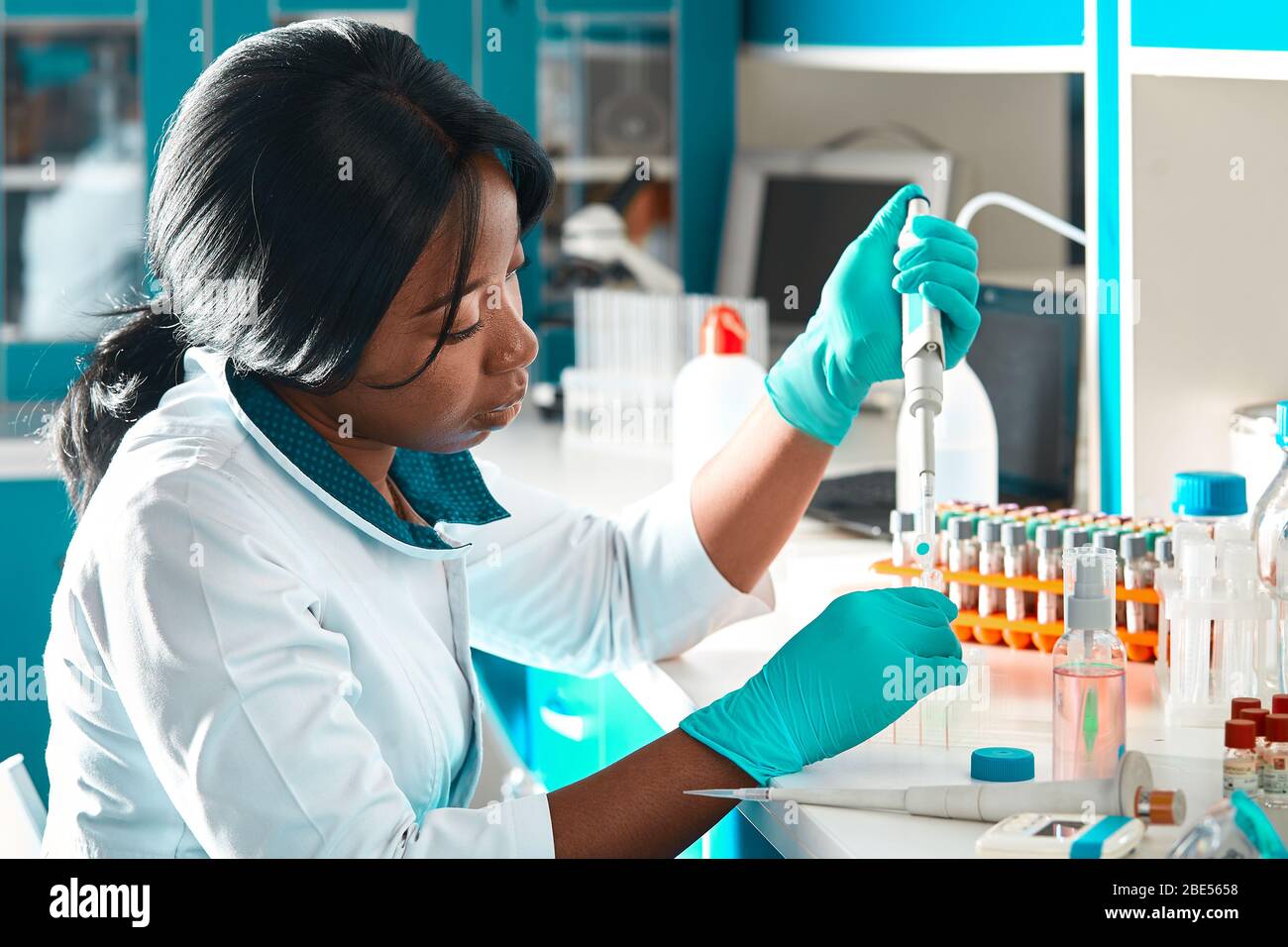 African scientist or graduate student in lab coat and protective wear ...