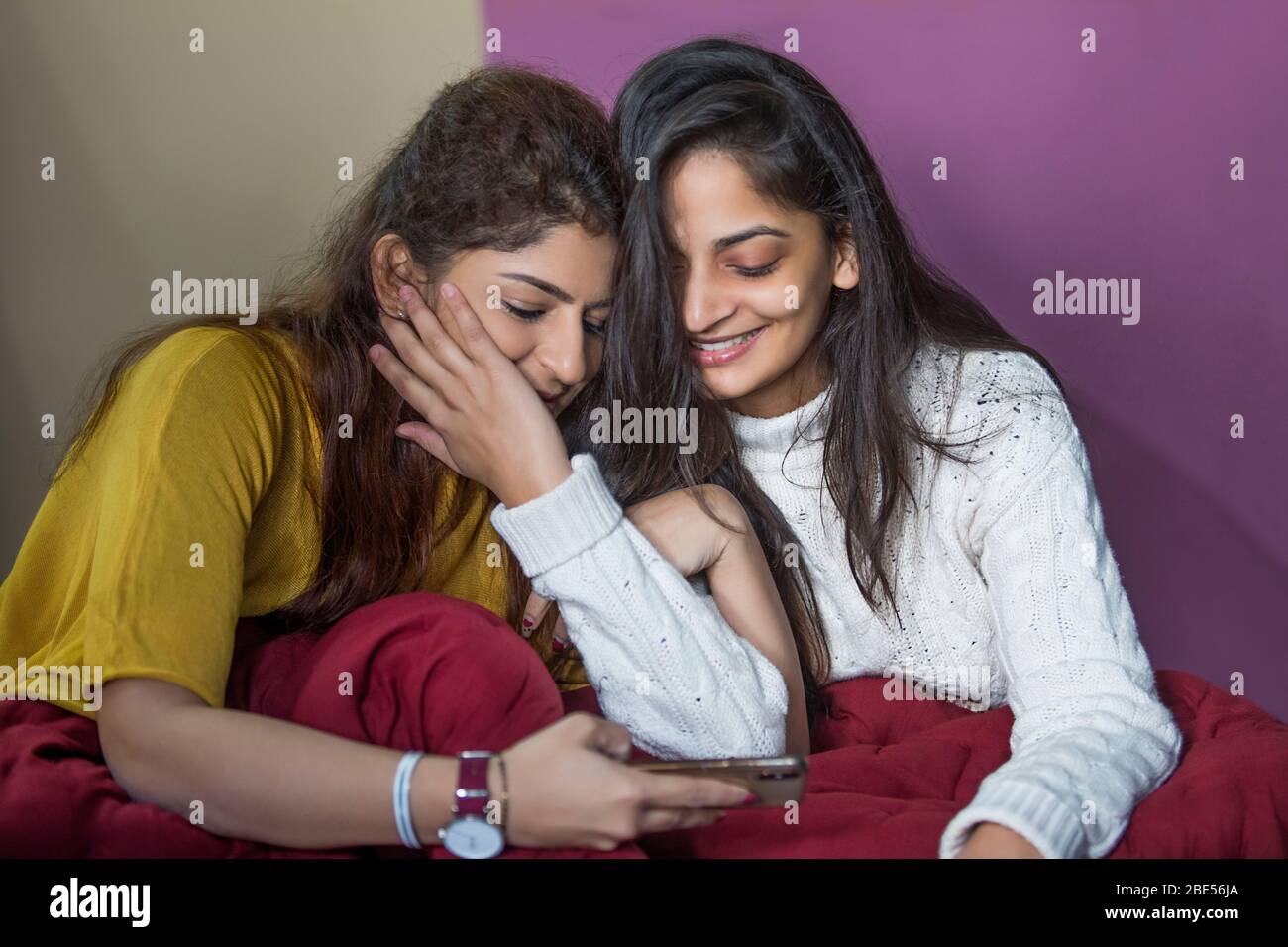 Sisters smiling and watching video on the mobile together Stock Photo ...