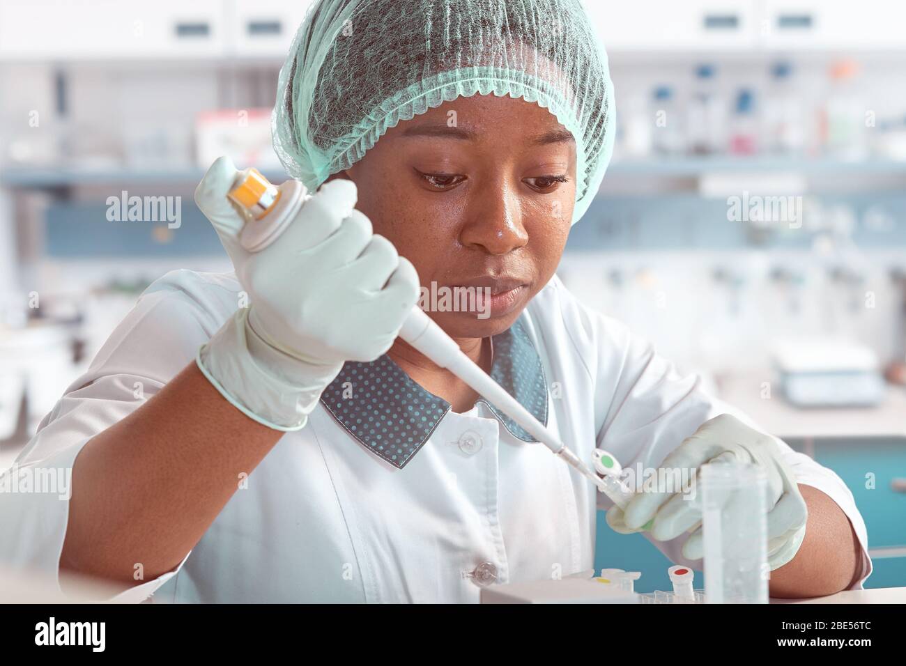 African scientist, technical assistant in lab coat, protective hat and ...