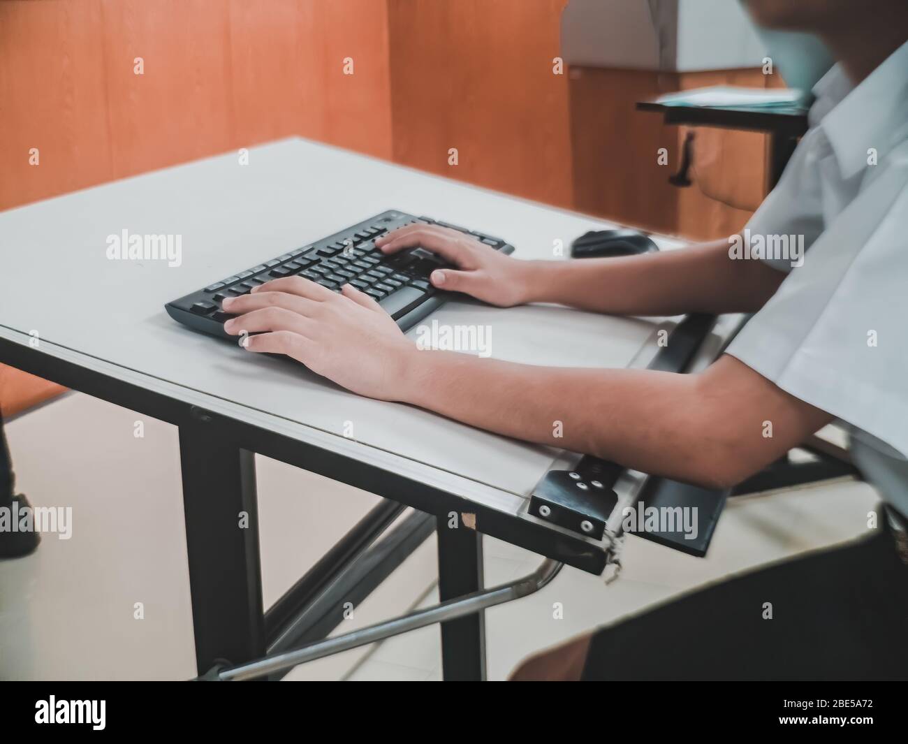 Asian student typing on wireless keyboard in classroom Stock Photo - Alamy