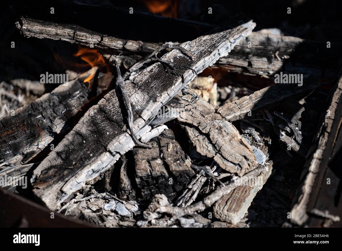 Dark pieces of wood burning in orange-yellow flame in the fire full of ...