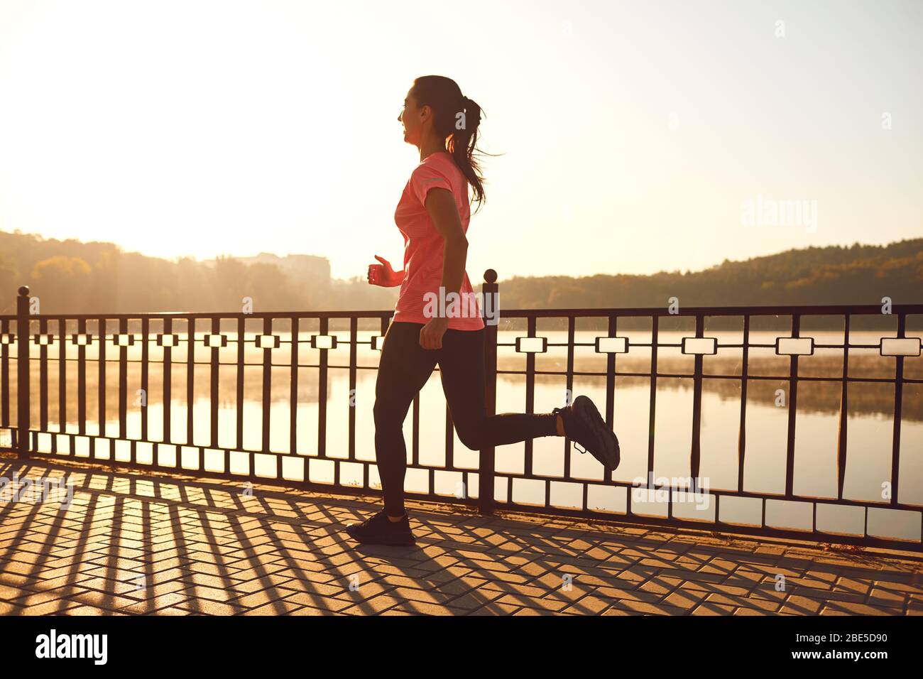 Girl runner runs in a park by the lake at dawn Stock Photo - Alamy
