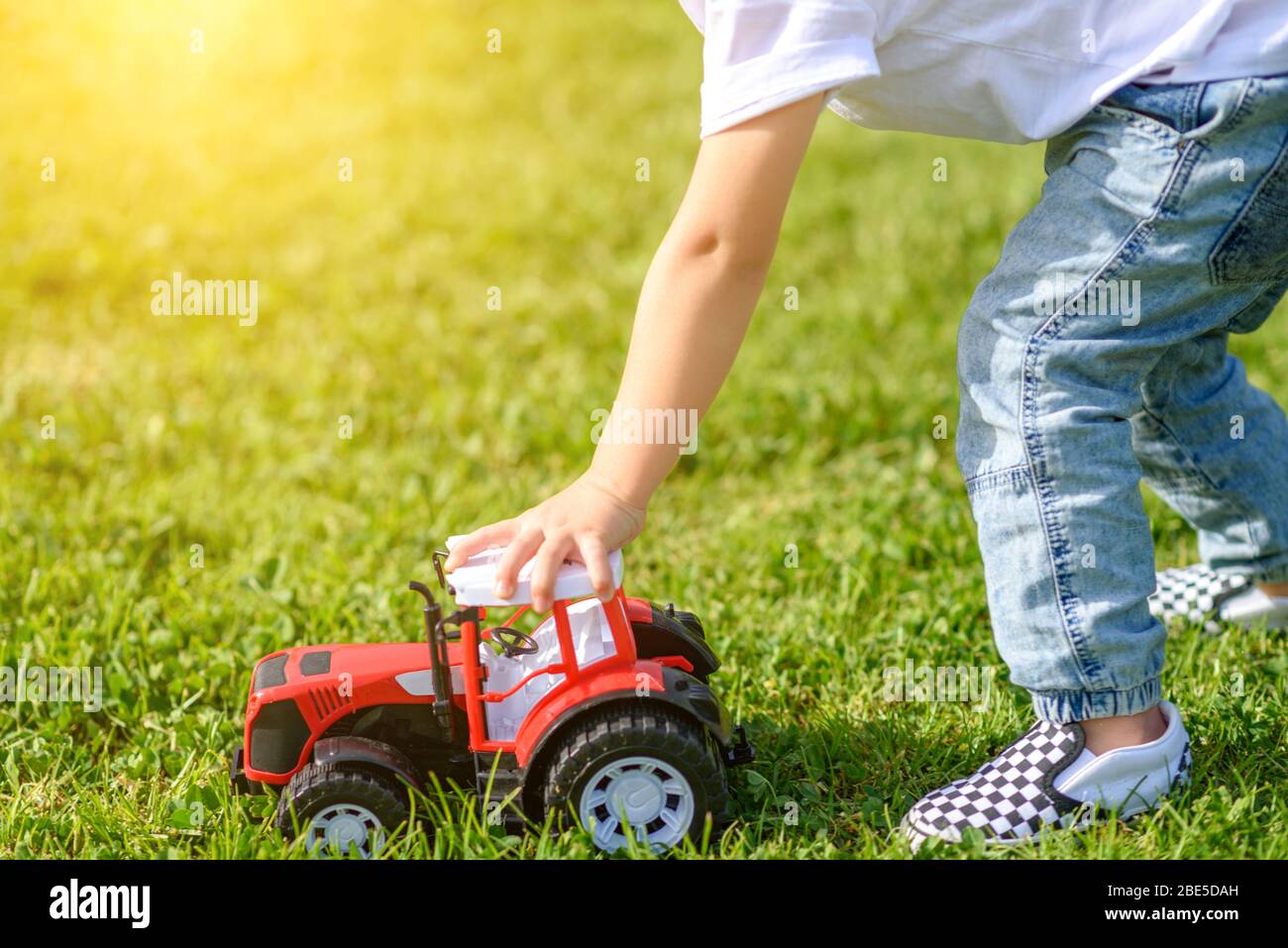 Child playing with red toy car on the grass outdoors in the park Stock ...
