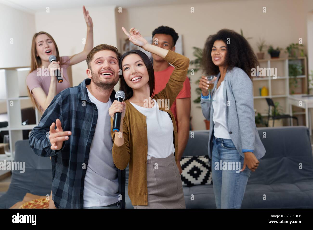 Karaoke party. Young happy couple or friends holding microphone and ...