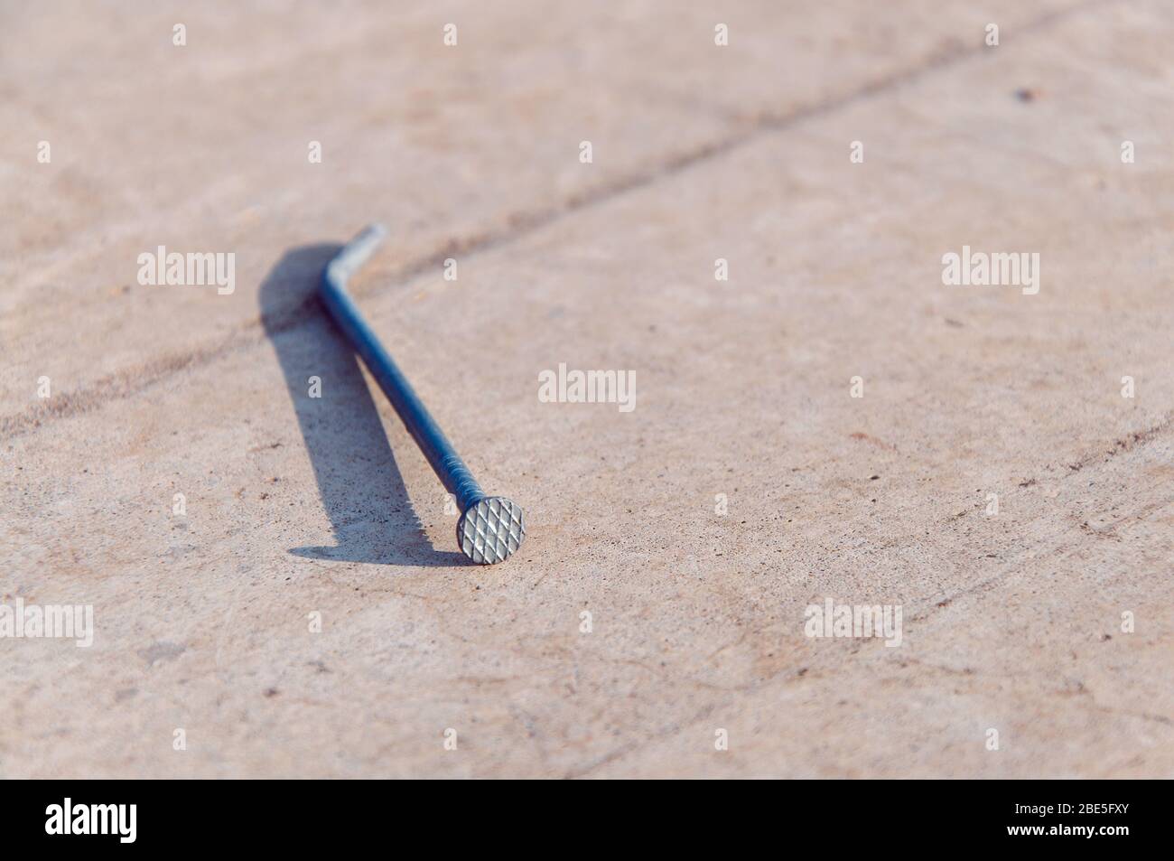 Construction nail. A large nail lies on a concrete base. Material for ...