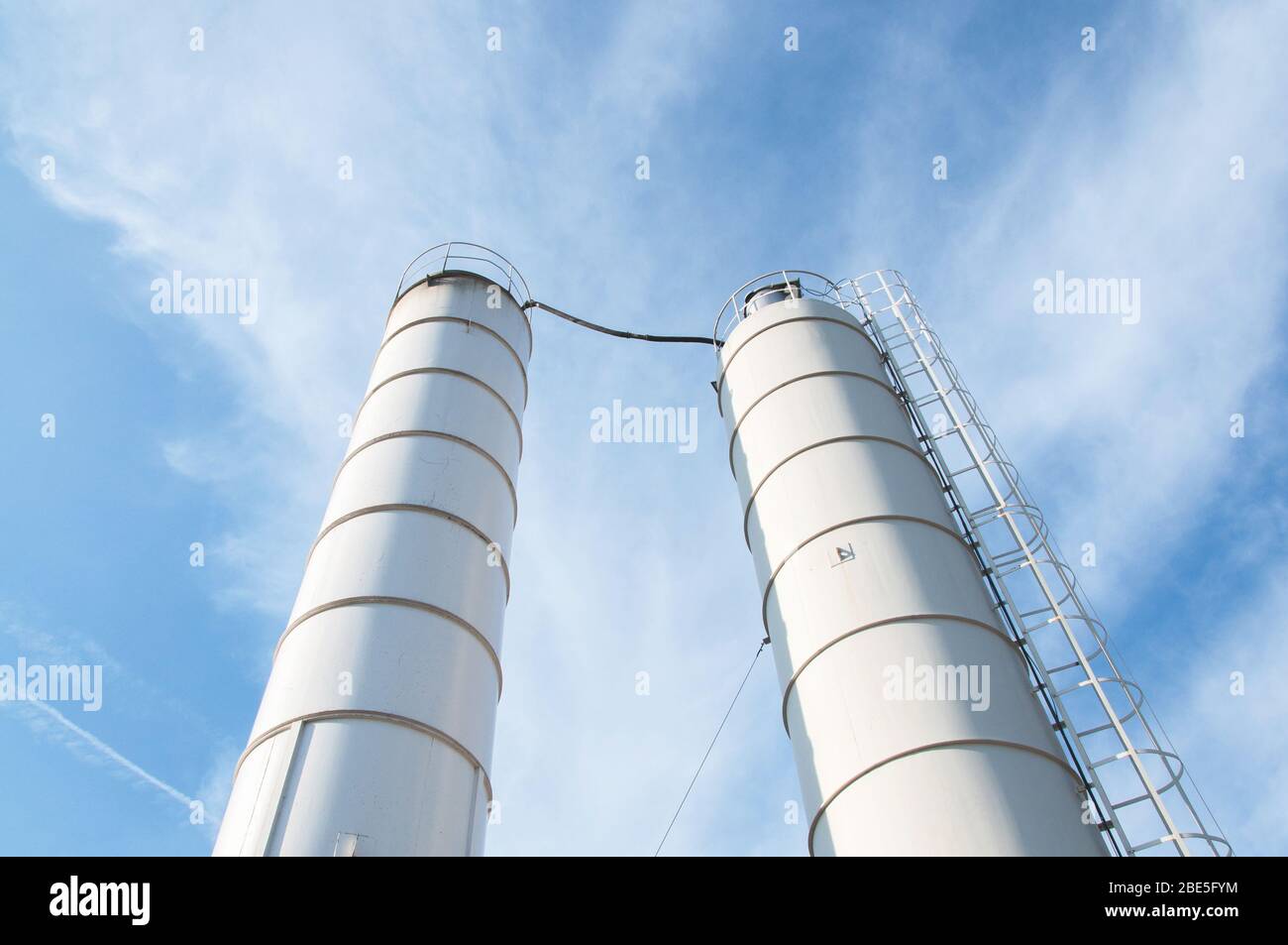 Silo for storage of cement. Cement factory machinery on a clear blue ...