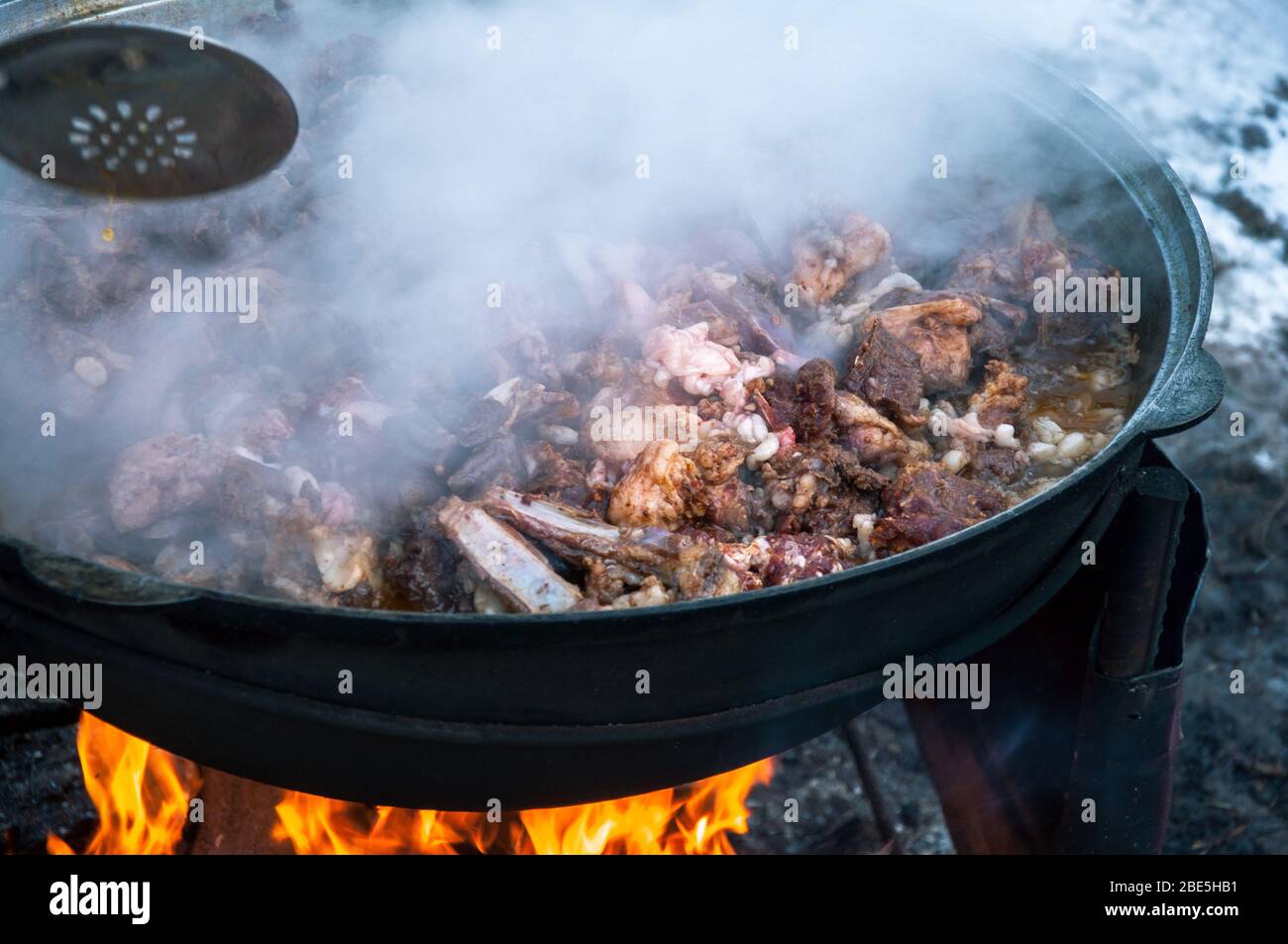 The meat is cooked in a cauldron on fire. Cooking a national dish Stock ...