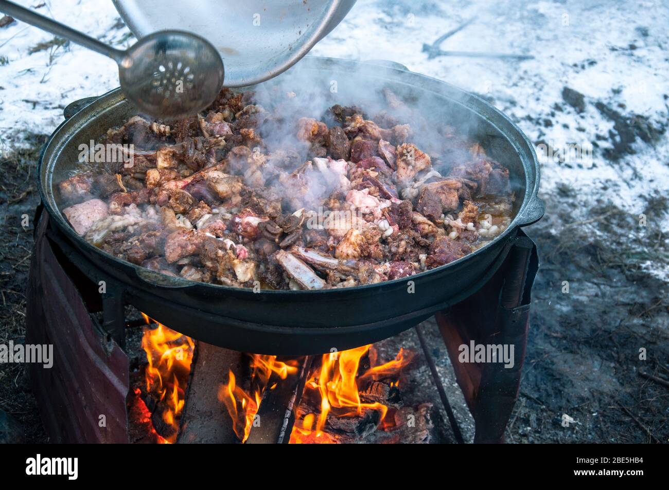 The meat is cooked in a cauldron on fire. Cooking a national dish Stock ...