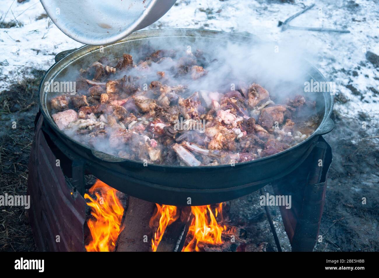 The meat is cooked in a cauldron on fire. Cooking a national dish Stock ...