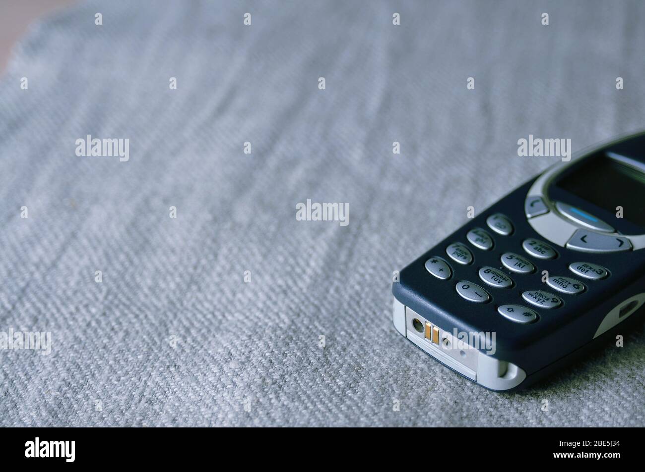 Old push-button mobile phone close-up on a fabric background. Old cell ...