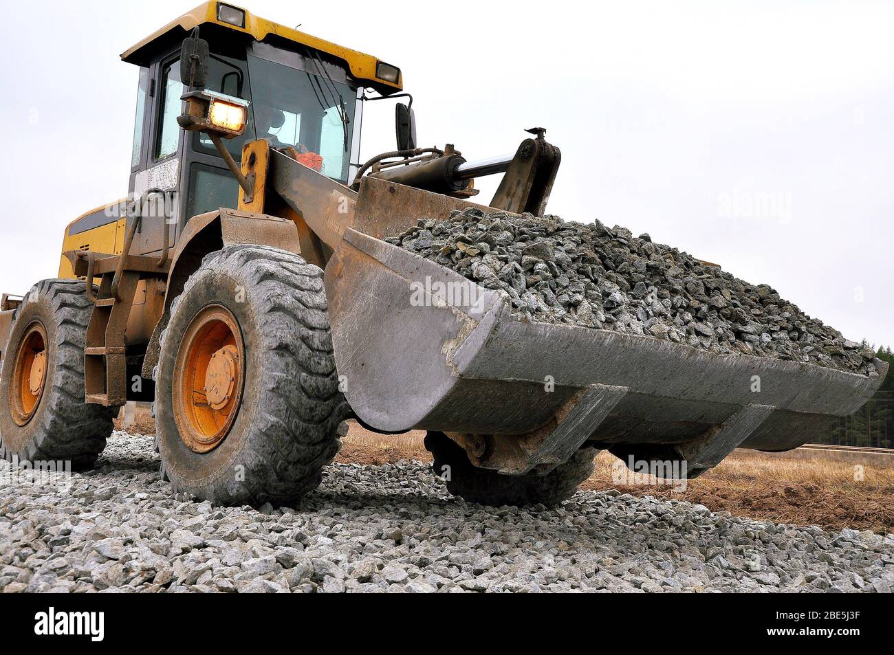 The front-end loader carries crushed stone to fill the road. Special ...
