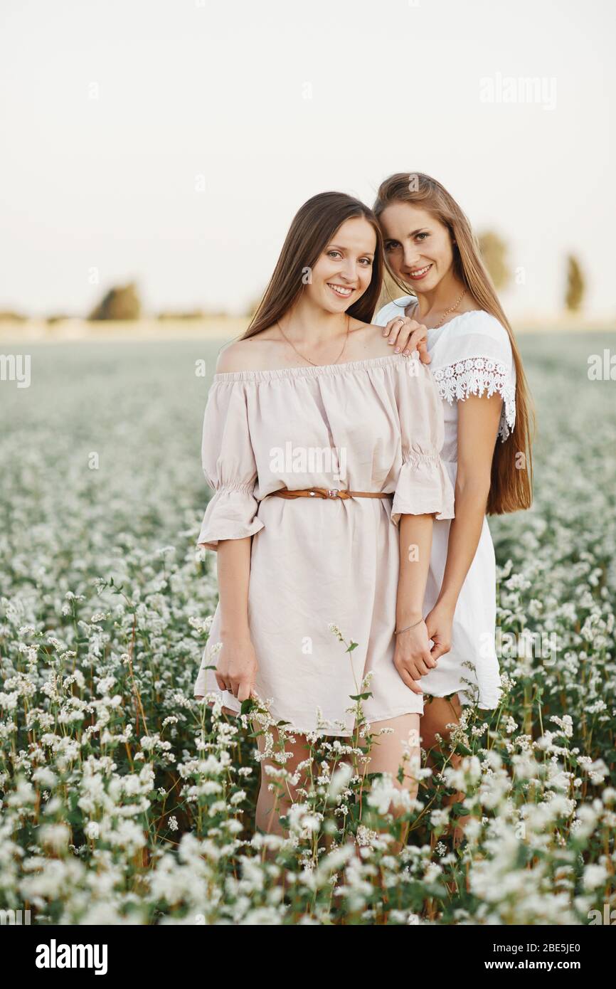 two pretty sisters in a field of flowers. Spring beauty concept ...