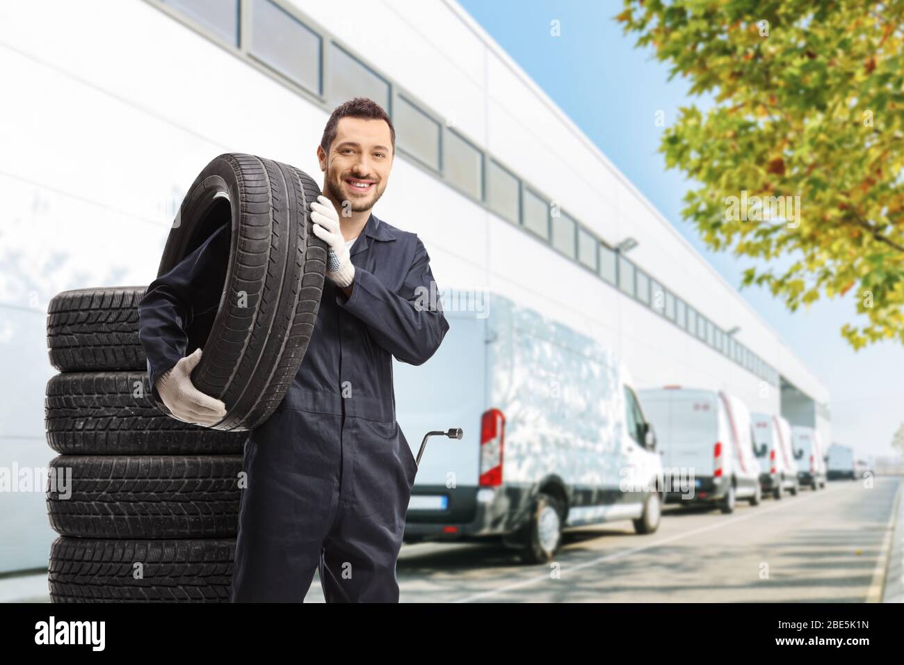Male worker in a uniform carrying car tires in front of a factory Stock ...