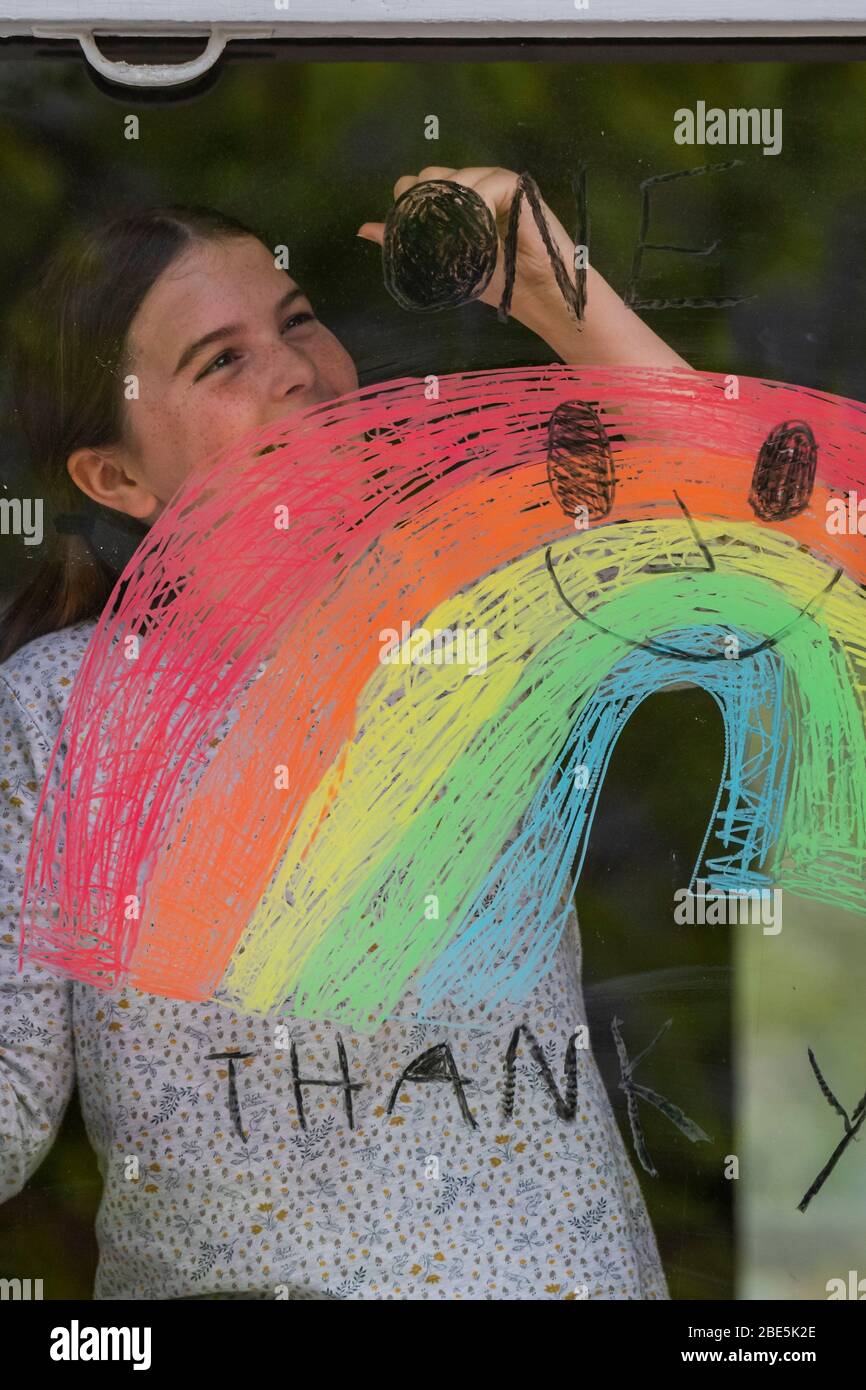 London, UK. 12th Apr, 2020. A young girl draws her rainbow message of ...