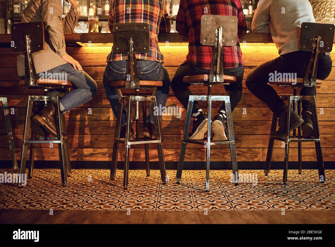 Rear view friends sitting on chairs talking at the bar in a bar Stock ...