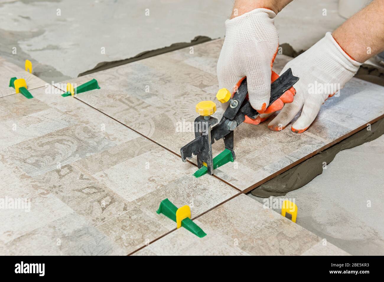 A worker is leveling the ceramic tile with wedges and clips Stock Photo ...