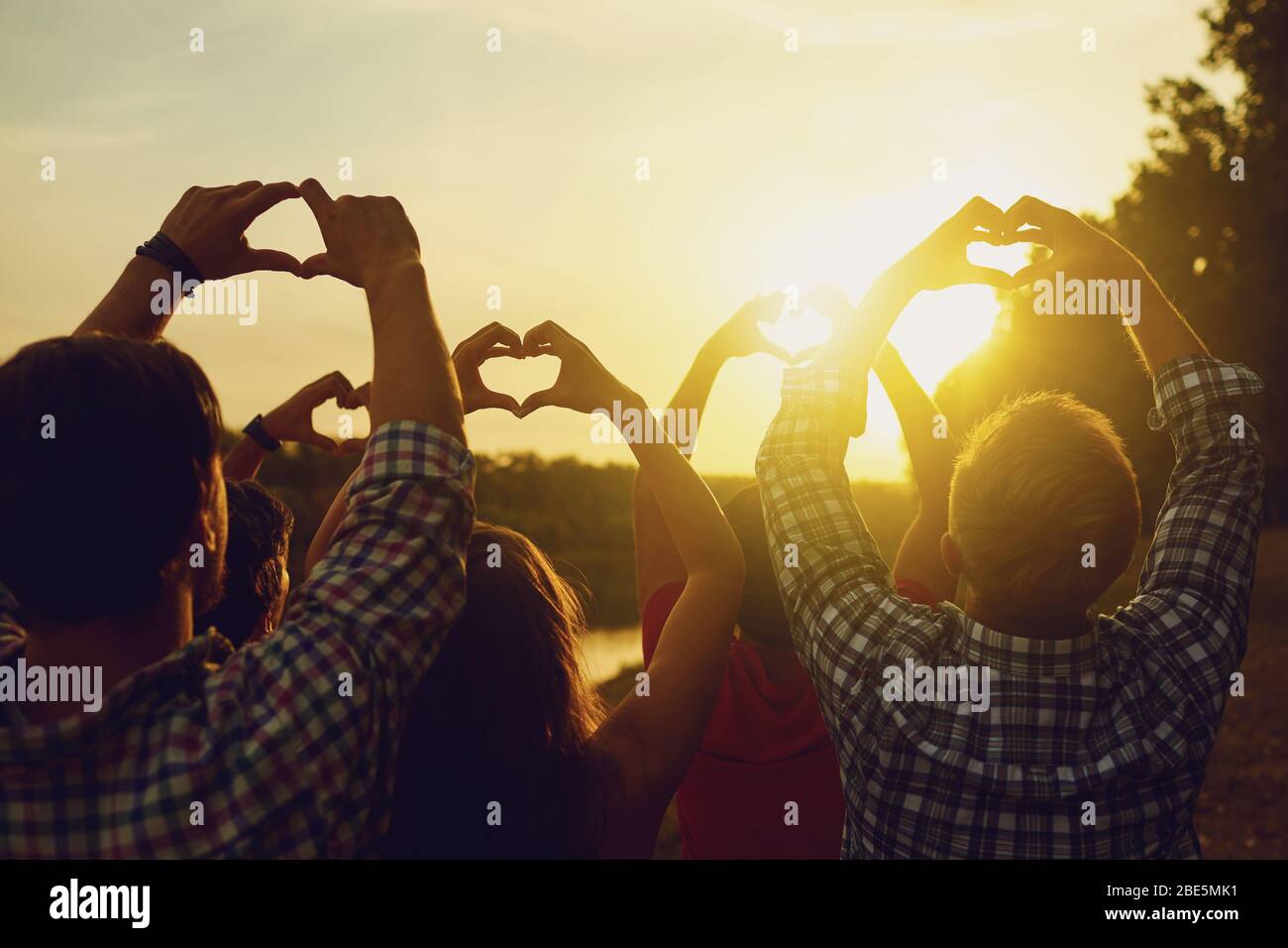 Heart sign with hands of a group of people at sunset. A group of ...