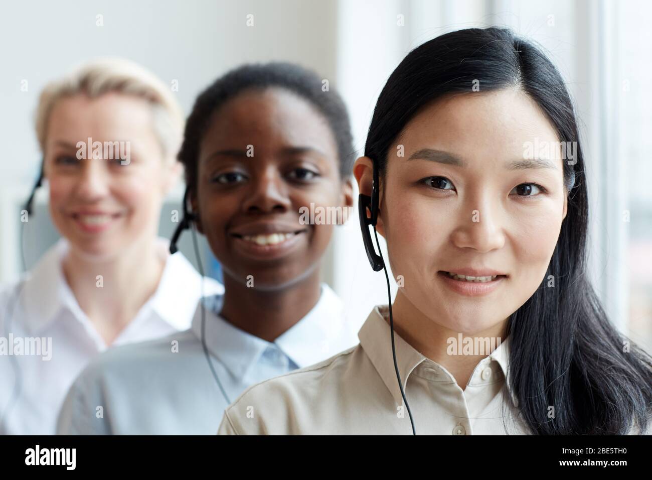 Multi-ethnic group of female call center operators looking at camera ...