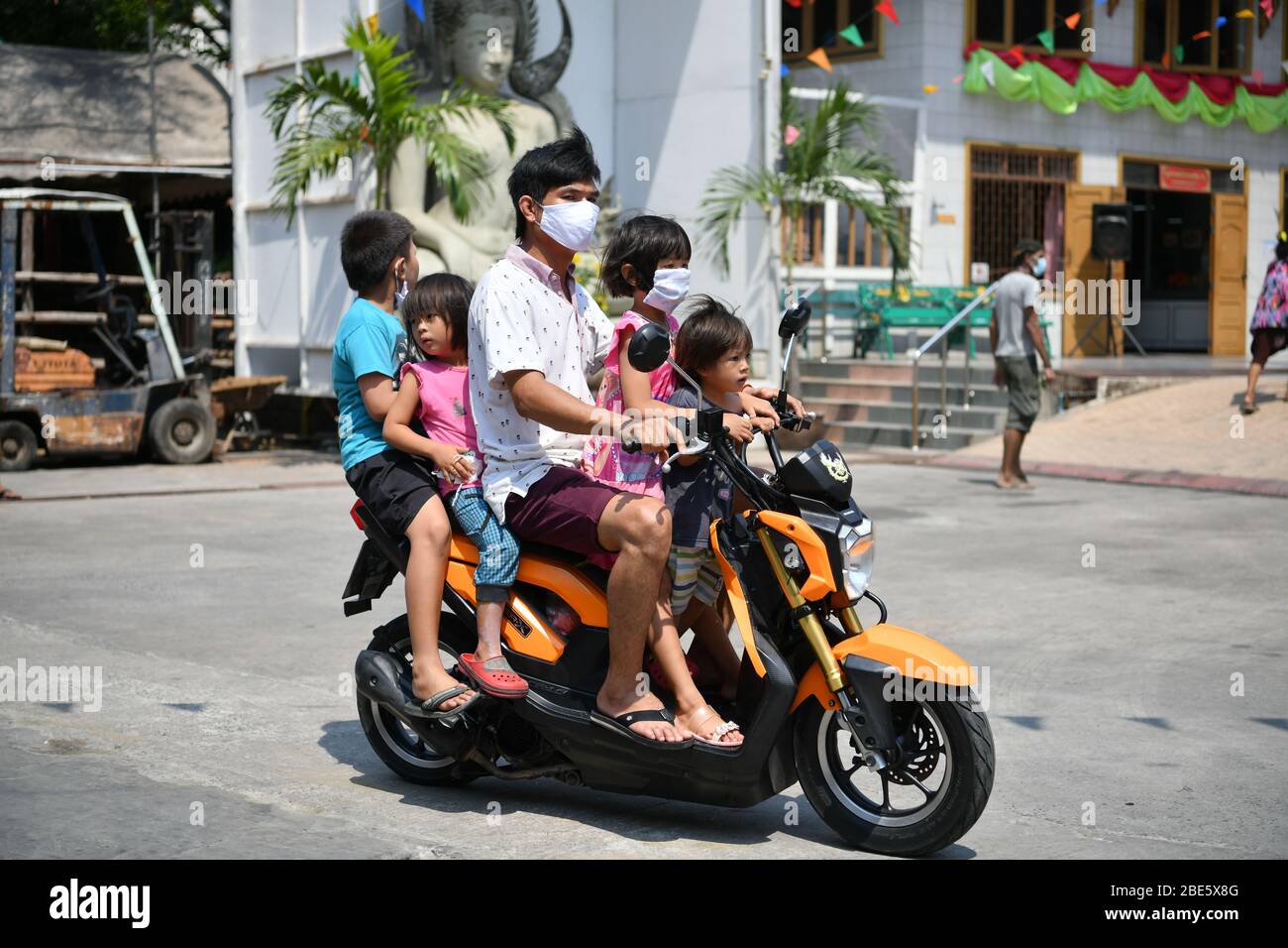 A motorcyclist with his family wear face masks as a preventive measure ...