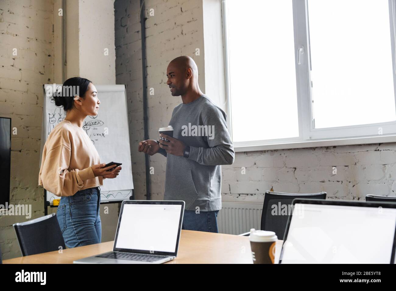 Image of a positive smiling colleagues talking with each other indoors ...