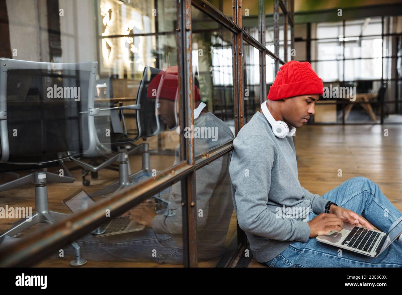 Image of young attractive african american man wearing hat using laptop ...