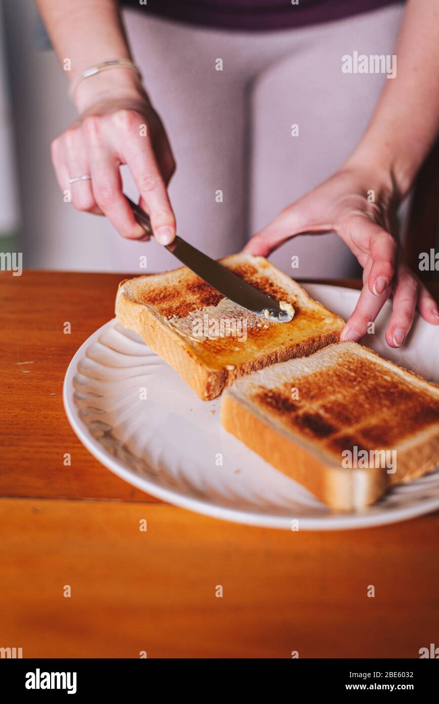 two hands spreading butter on toast Stock Photo - Alamy