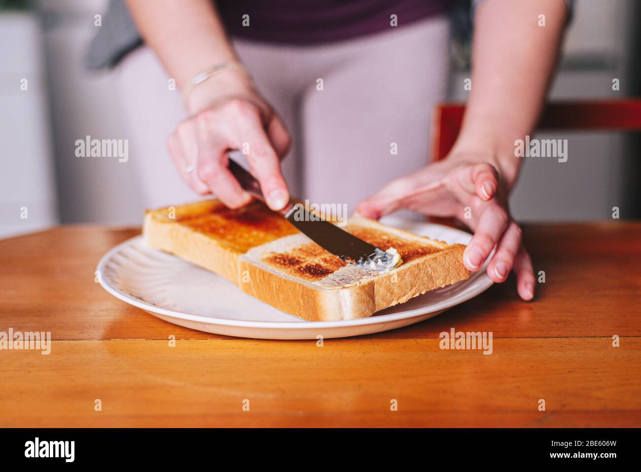 two hands spreading butter on toast Stock Photo - Alamy