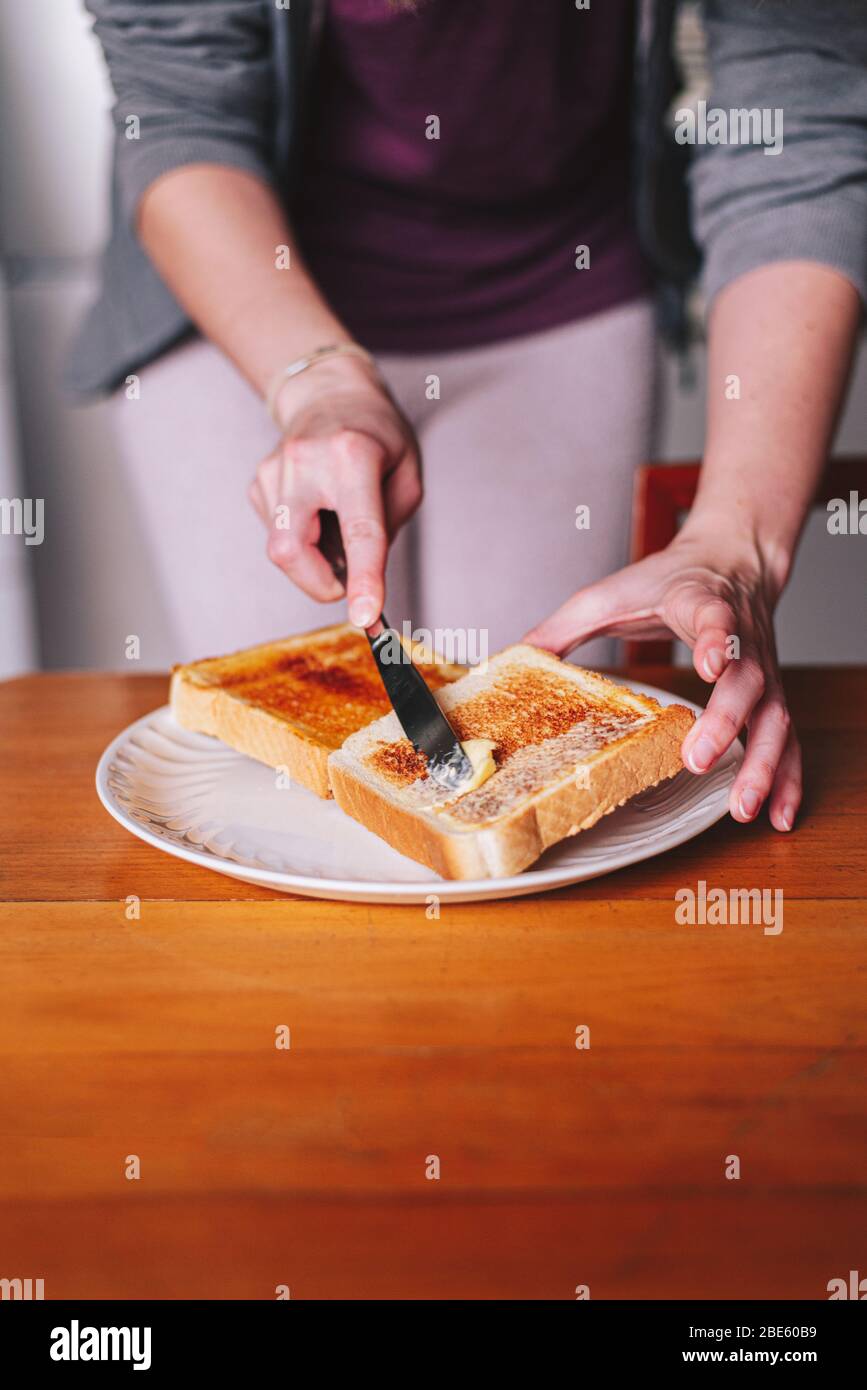 two hands spreading butter on toast Stock Photo - Alamy