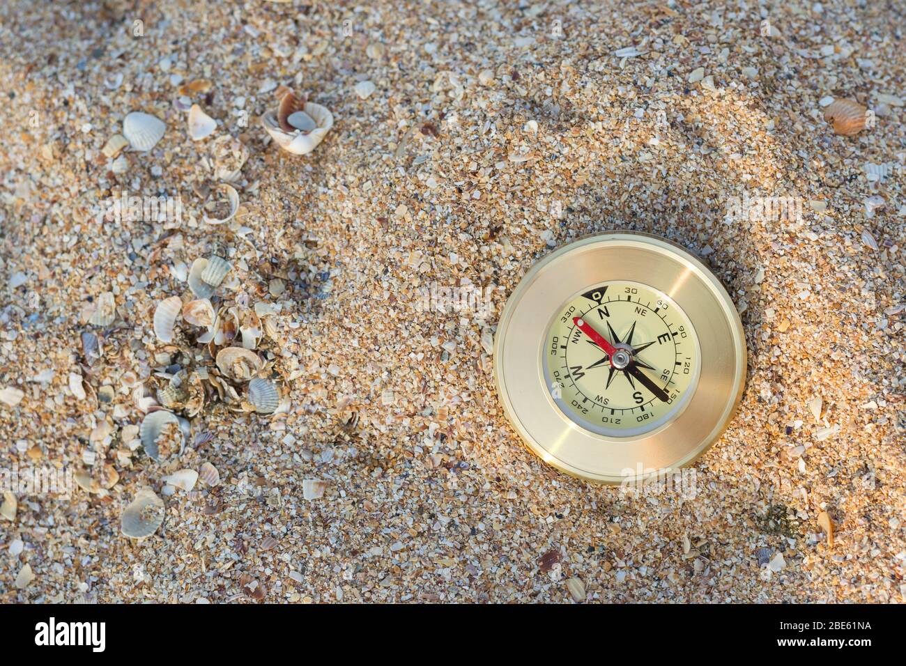 A compass showing the direction lies on sand with seashells Stock Photo ...