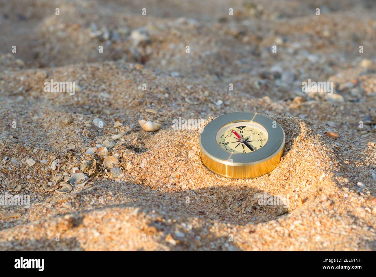 A compass showing the direction lies on sand with seashells Stock Photo ...
