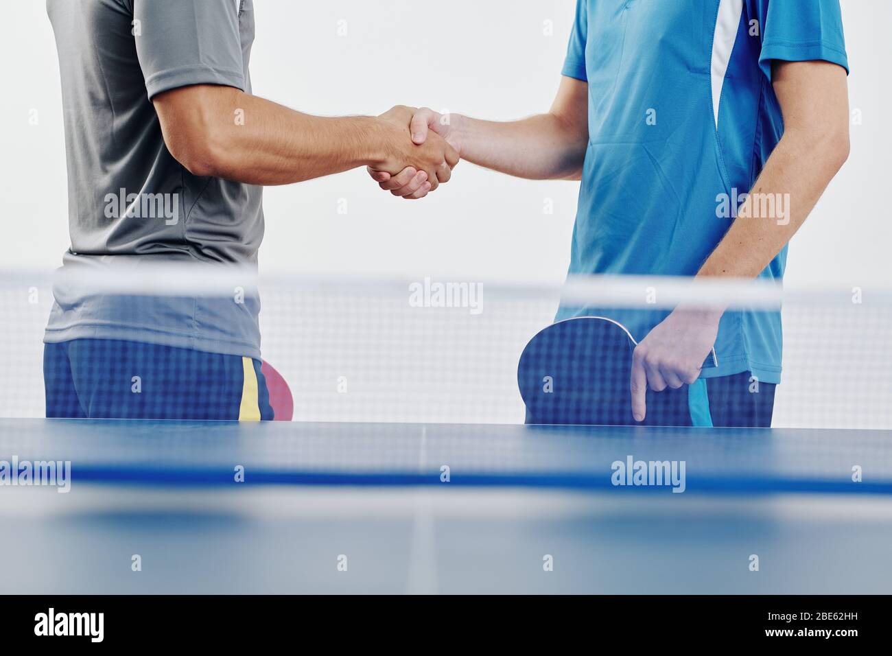 Cropped image of table tennis players shaking hands before playing game ...