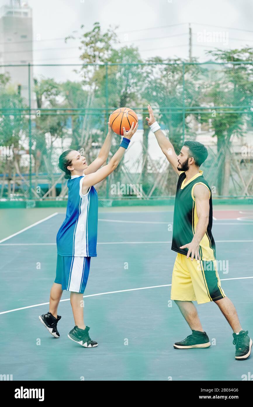 Multi-ethnic young people playing basketball on street basketball court ...