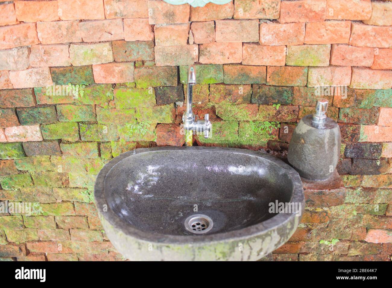 Black stone wash basin and vintage green mirrors. Retro orange brick ...