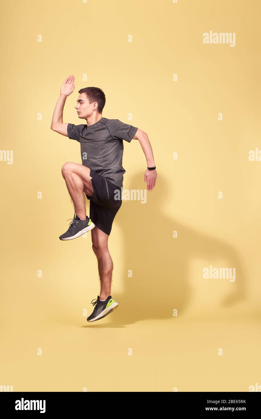 Side view of athlete man running in studio on yellow background Stock ...
