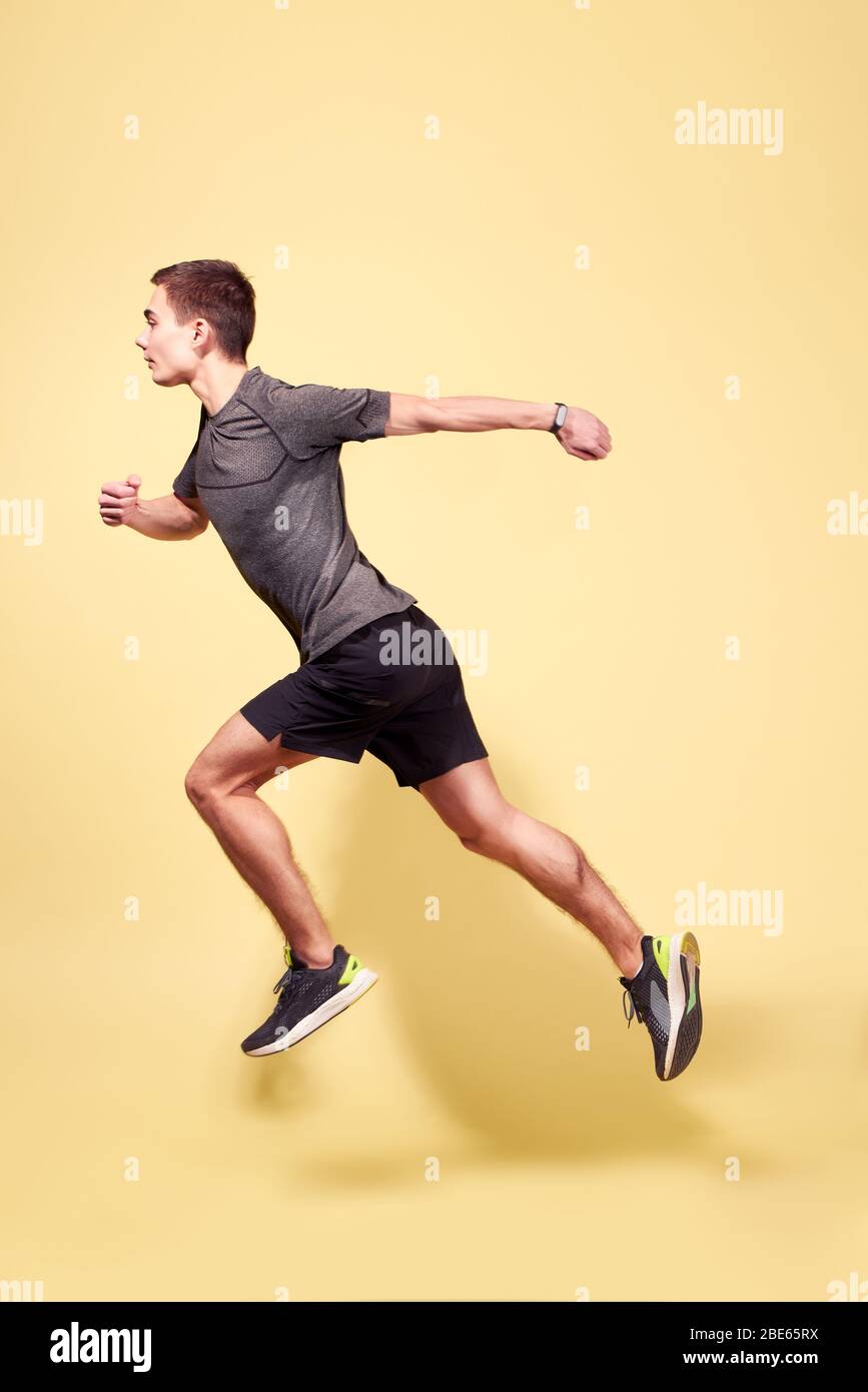 Side view of young athlete running in studio on yellow background Stock ...