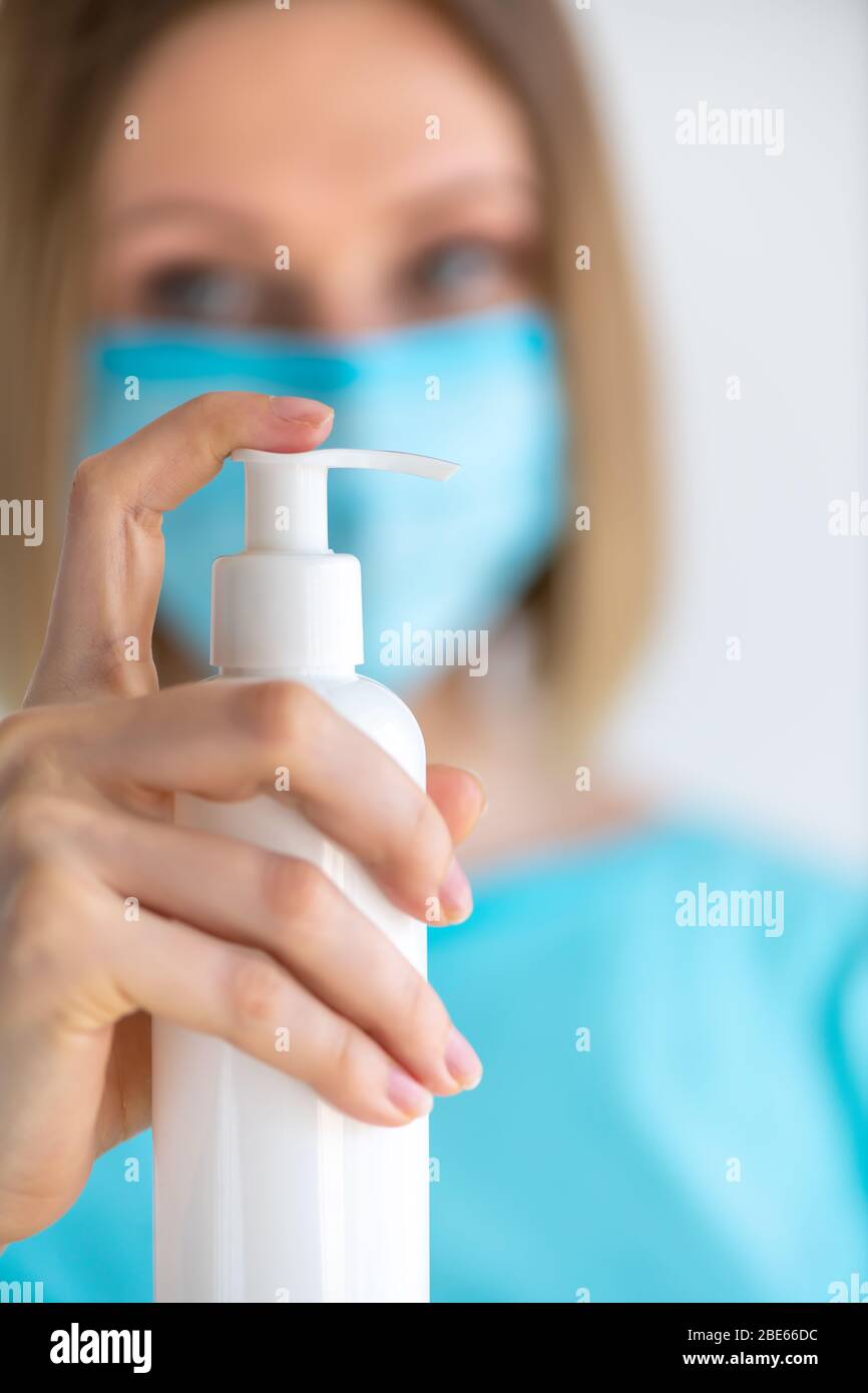 Female doctor or nurse in uniform puts a disinfectant soap on her hands ...