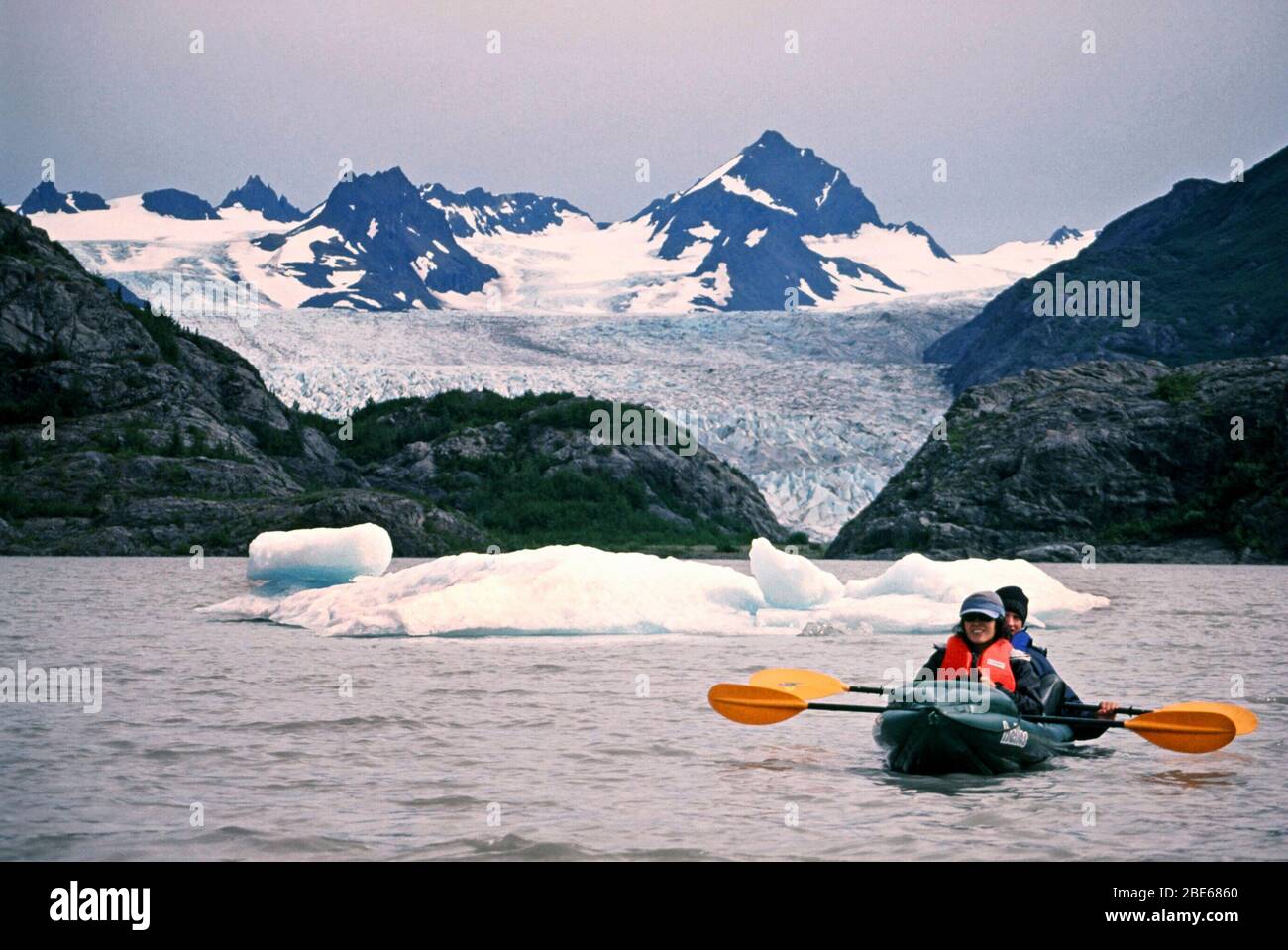 Mother and son in warm jackets, hats and life vests paddle a kayak past ...