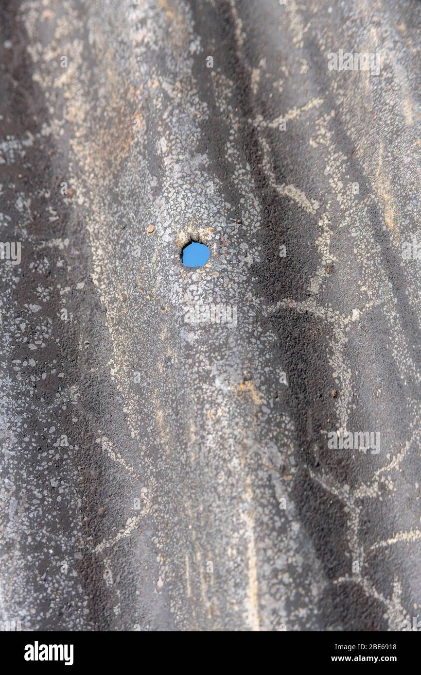 Sheet of corrugated steel which has seen better days and fixing bolt ...