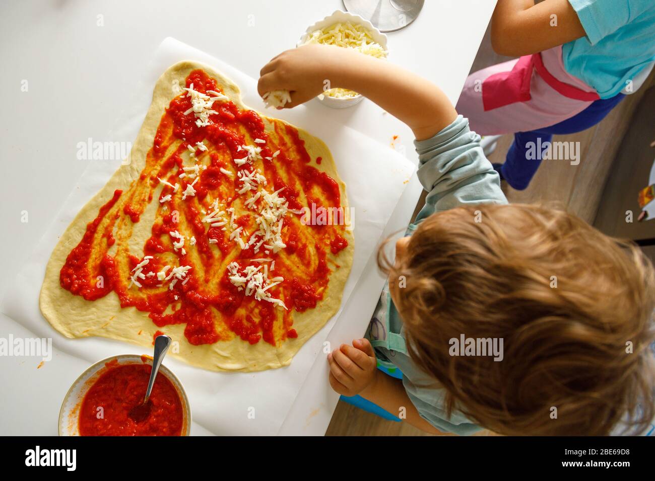Little boy throwing grated cheese on a pizza Stock Photo - Alamy