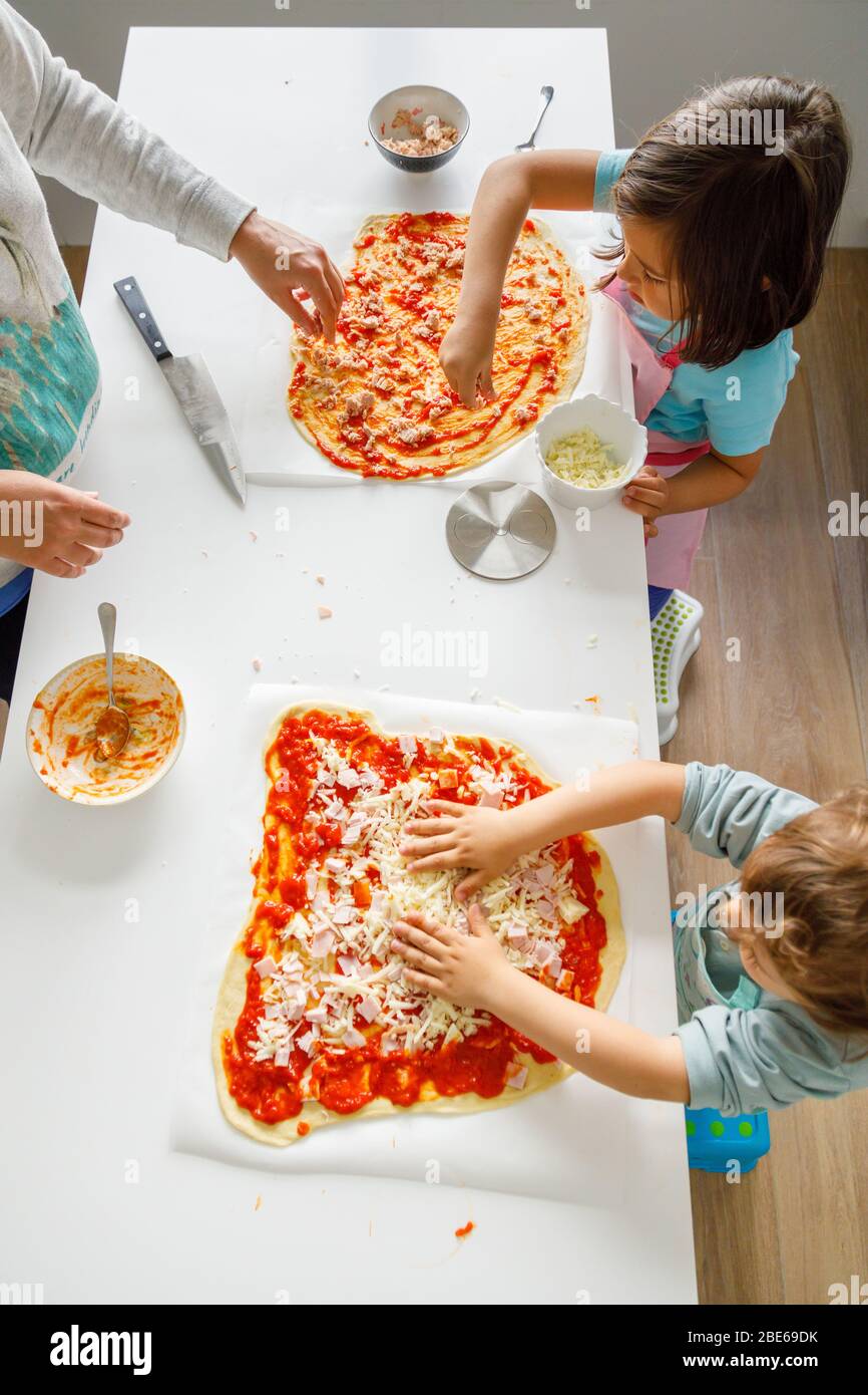 A girl and a boy preparing a homemade pizza with their mother in the ...