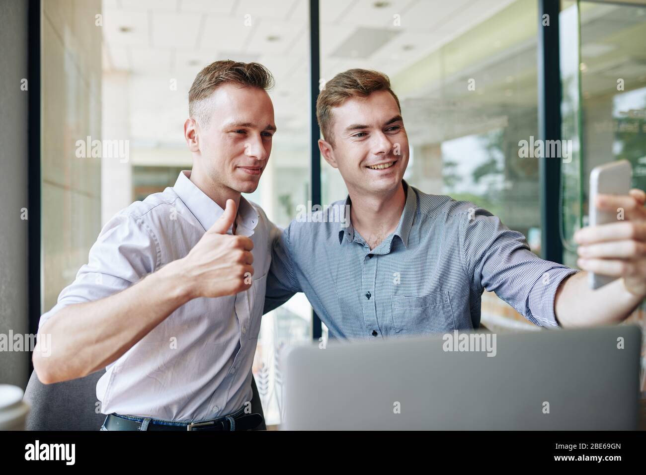 Cheerful colleagues hugging and taking selfie on smartphone after ...